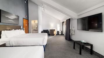 Quarto de hotel com duas camas, televisão de tela plana, escrivaninha e uma janela grande.