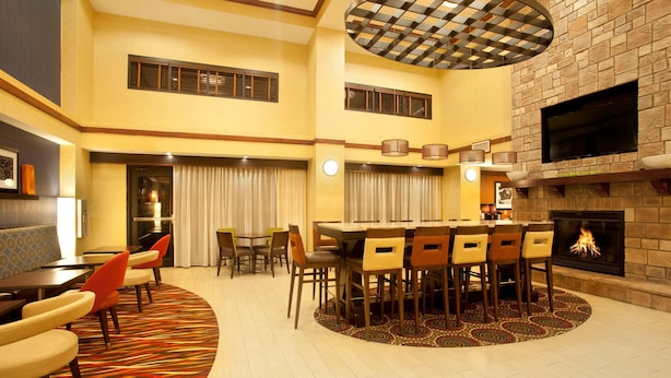 Um amplo hall de hotel com área de refeições, lareira e televisão na parede.