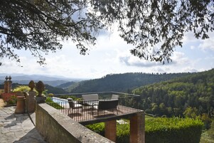 Terraço com mobiliário de exterior com vista para uma paisagem montanhosa.