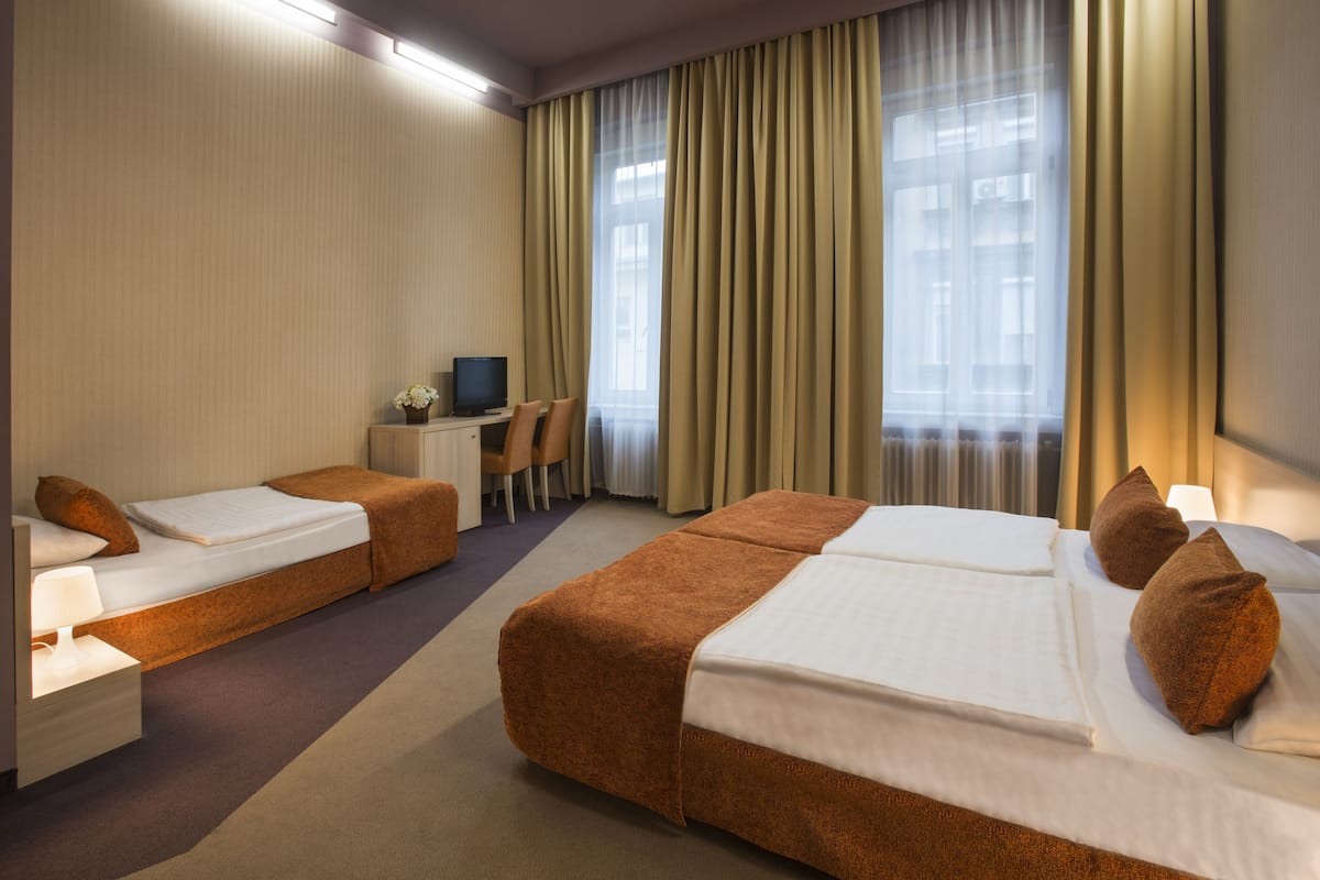 Quarto de hotel com duas camas, uma escrivaninha e uma cadeira.