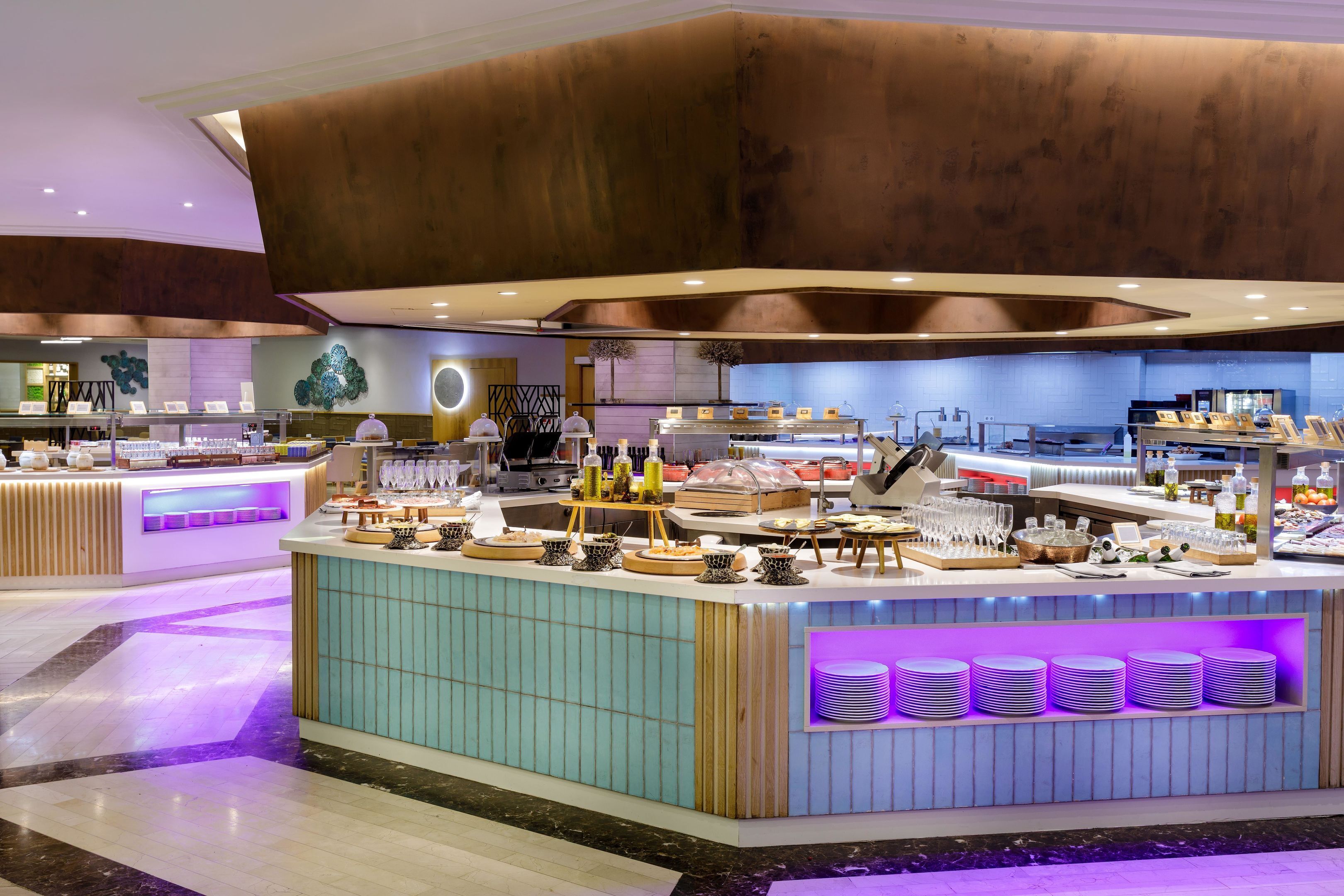 Um lobby de hotel moderno com um balcão de recepção central, área de estar e disposição de buffet.