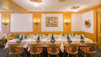 Uma sala de jantar com uma mesa comprida posta para refeição, cercada por cadeiras de madeira.
