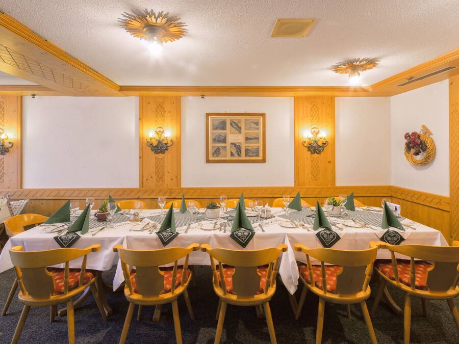 Uma sala de jantar com uma mesa comprida posta para refeição, cercada por cadeiras de madeira.