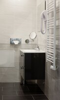 Uma casa de banho moderna com um armário preto, um espelho redondo, um porta-toalhas e um aquecedor embutido.