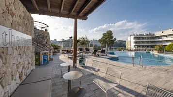 Uma área à beira da piscina com um muro de pedra, uma placa com a inscrição "the view" e assentos ao ar livre.