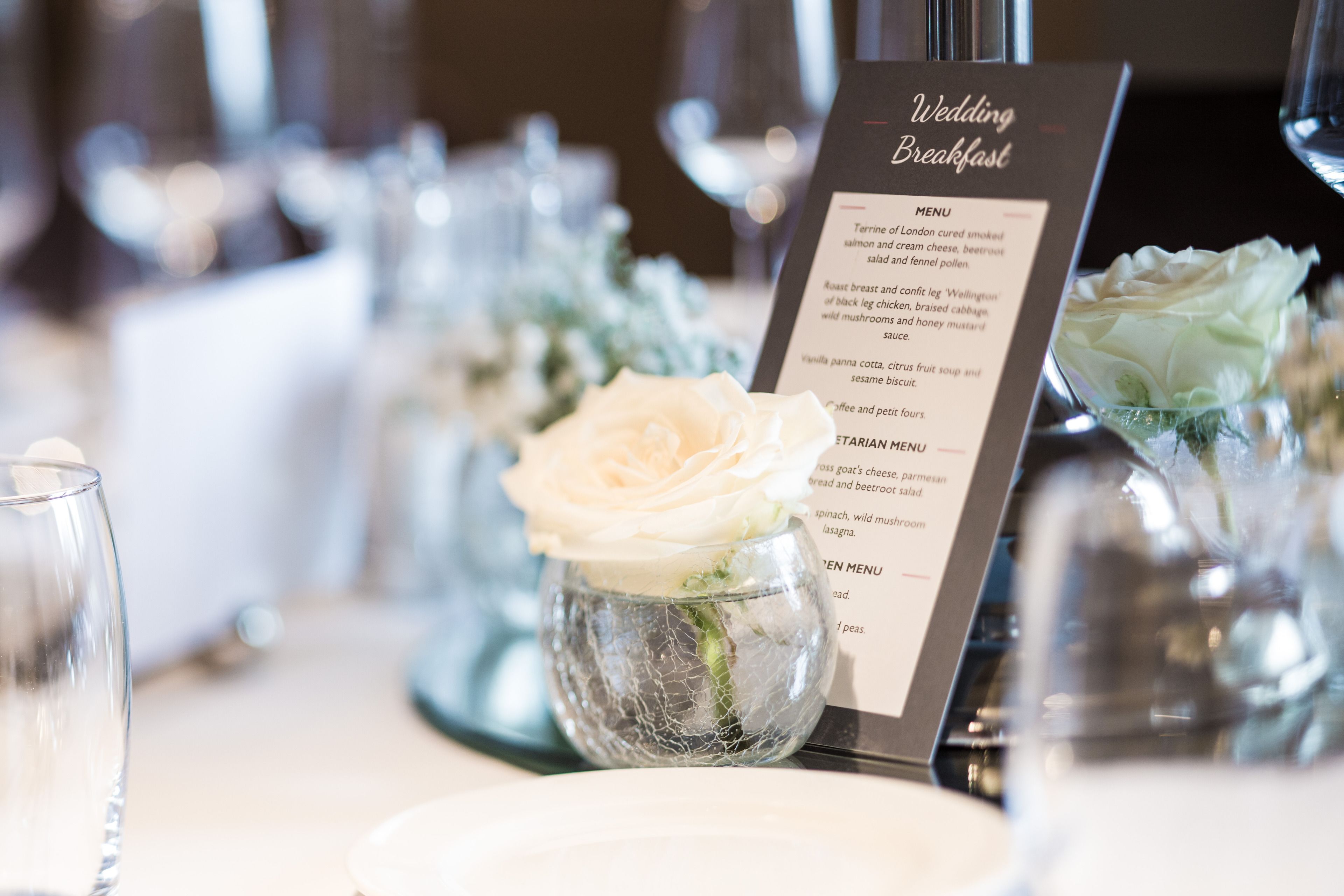 Menu de café da manhã de casamento com uma rosa branca em um vaso de vidro.