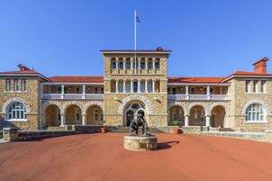 Um edifício histórico com pátio central, janelas em arco e um mastro.