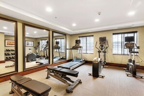 Academia com equipamentos de ginástica, um espelho e esteira.
