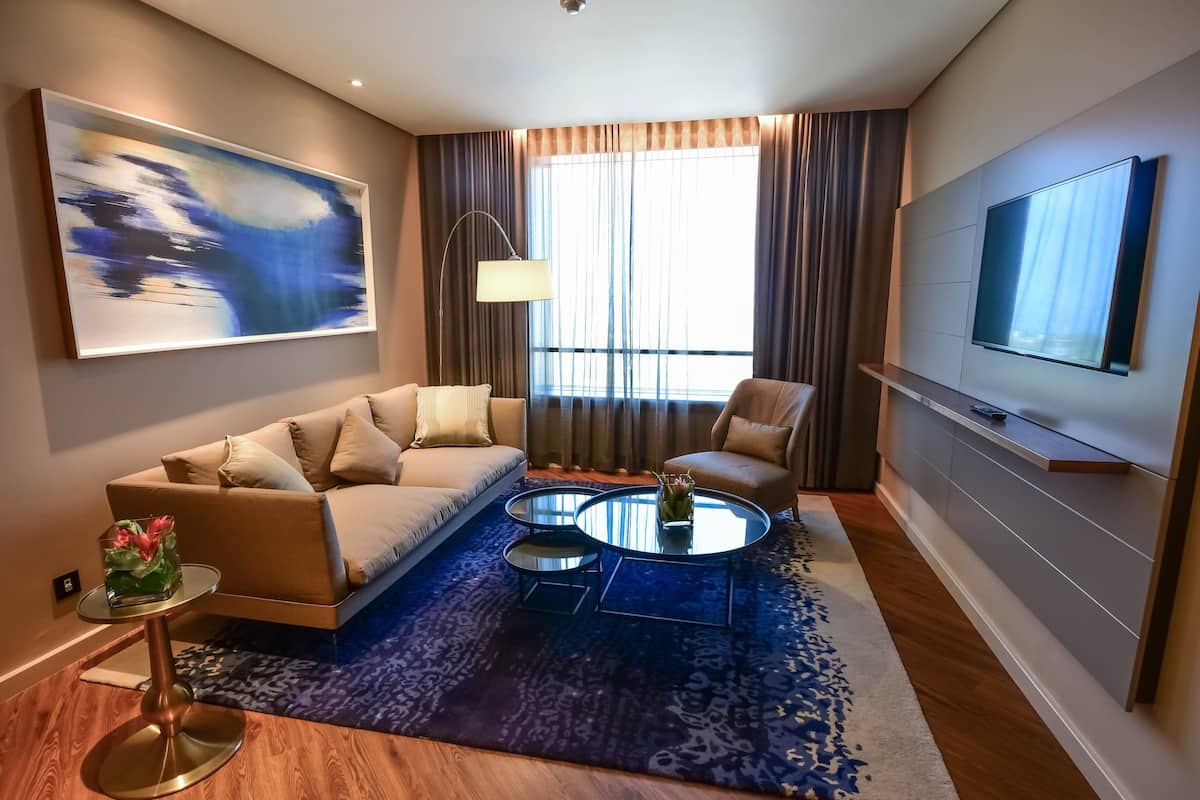 Uma sala de estar moderna com sofá, poltrona, mesa de centro e uma TV de tela plana fixada na parede.