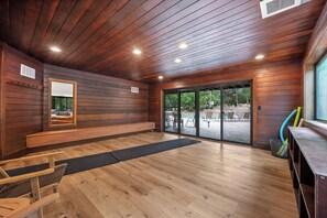 Interior de madeira com um banco, uma janela grande e vista para um pátio externo.