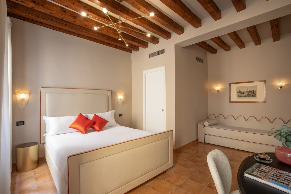 Quarto com cama, mesa de cabeceira e sofá.