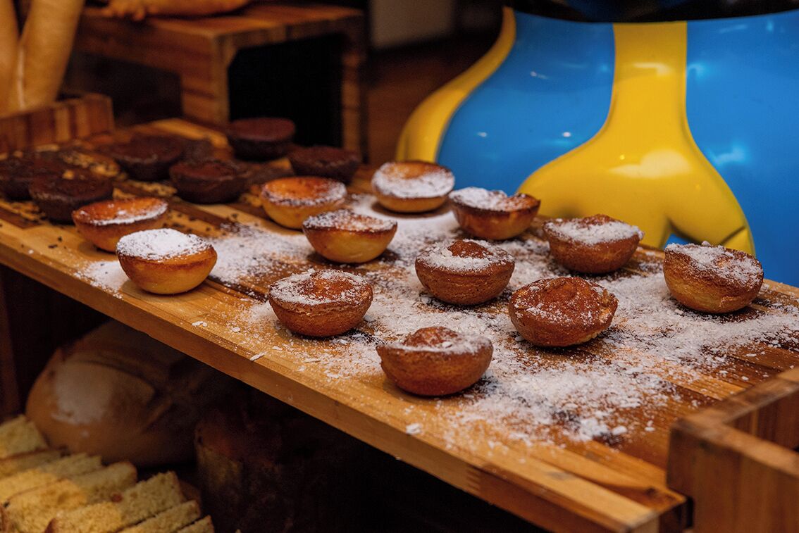 Uma mesa de madeira com vários doces pequenos polvilhados com açúcar em pó.