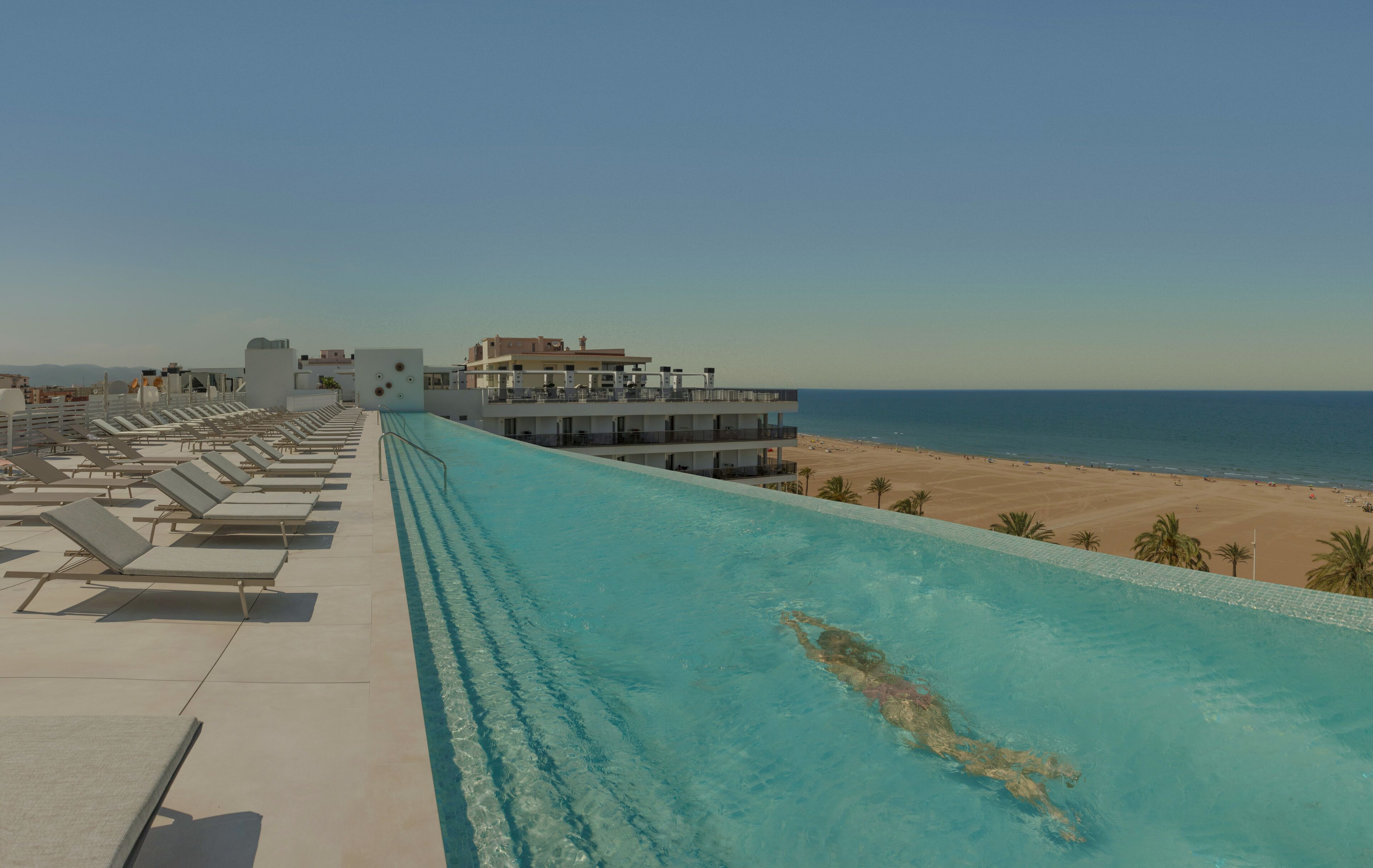 Piscina infinita no terraço, com vista para a praia e o oceano.
