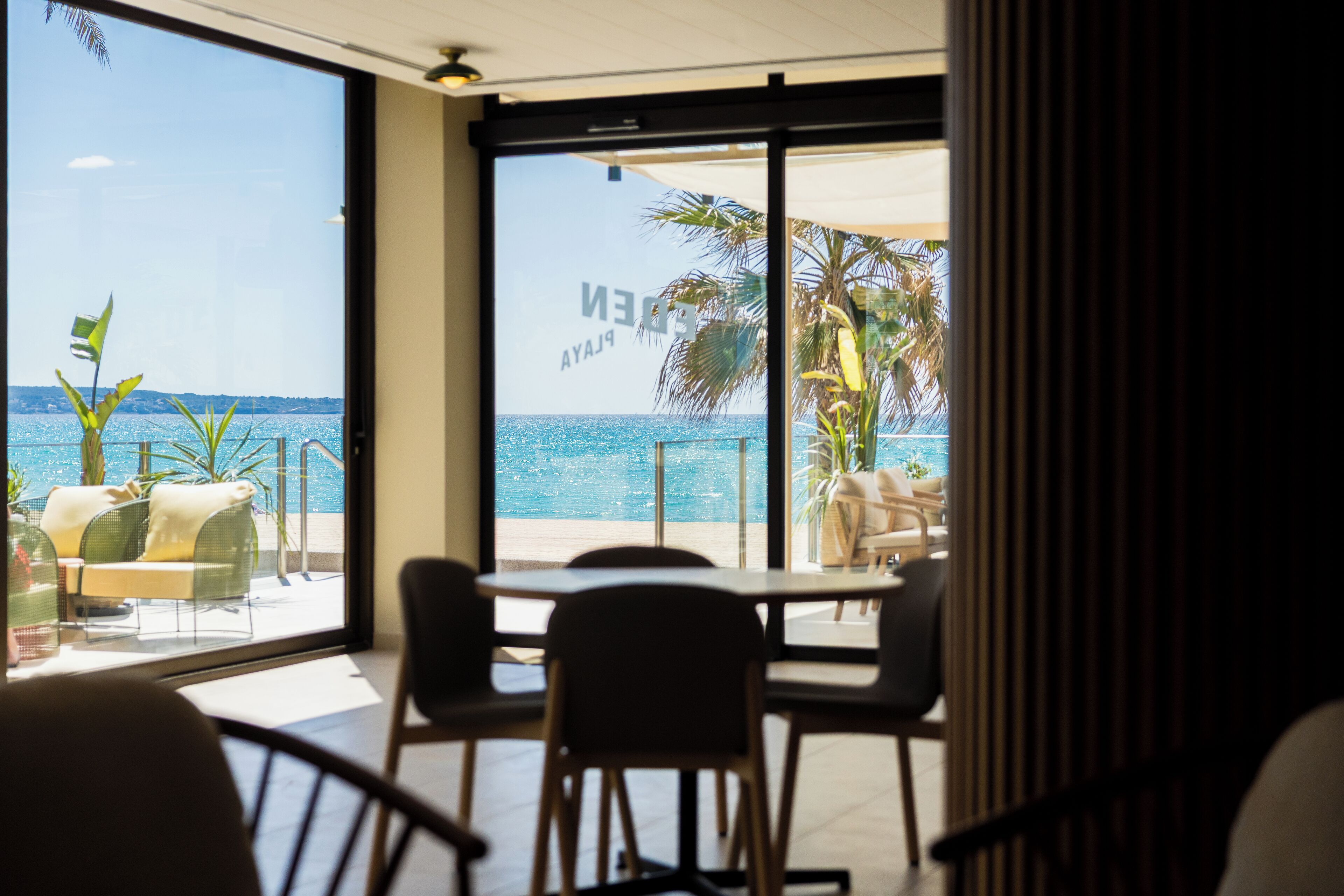 Quarto com uma grande janela de vidro com vista para a praia e para o mar.