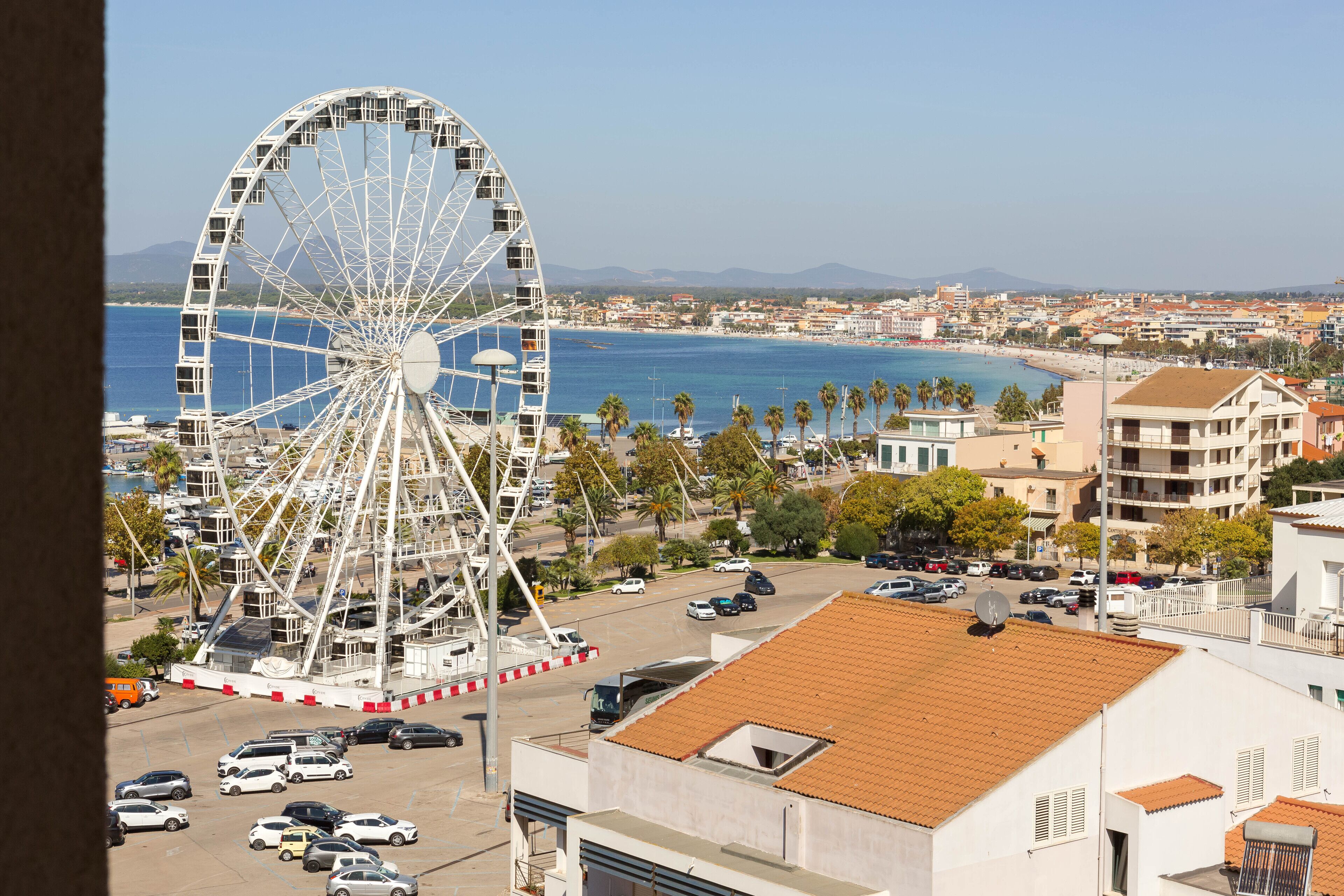 Uma roda gigante, uma praia e um estacionamento com carros.