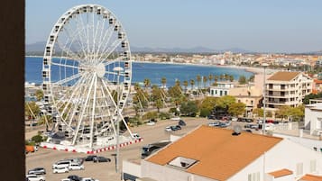 Uma roda gigante, uma praia e um estacionamento com carros.