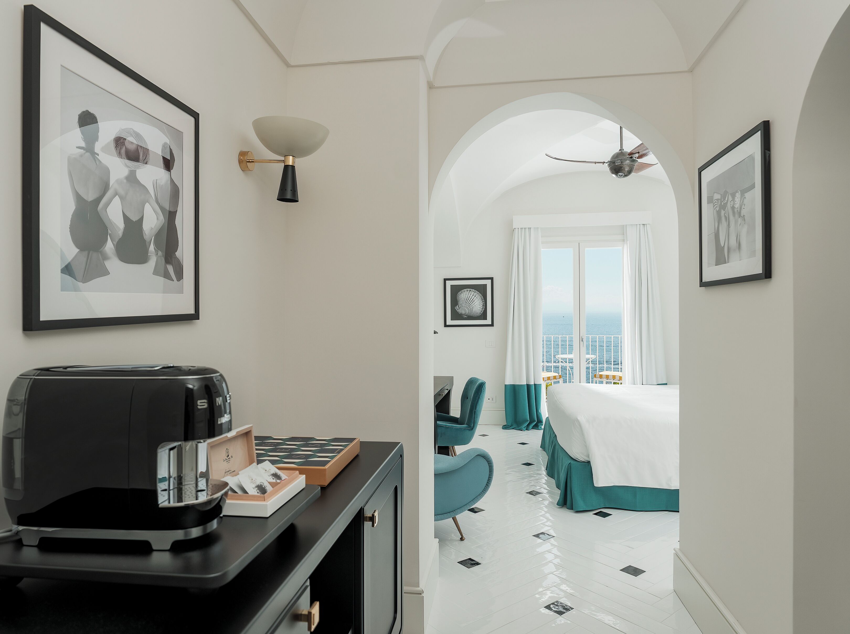 Quarto de hotel com vista para o oceano, área de refeições e cozinha compacta.