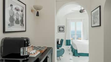 Quarto de hotel com vista para o oceano, área de refeições e cozinha compacta.