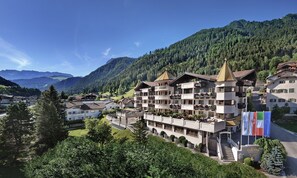 Um hotel com várias varandas, rodeado por vegetação exuberante e montanhas.