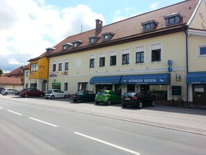 Um hotel com fachada amarela, várias janelas e telhado de telhas vermelhas.