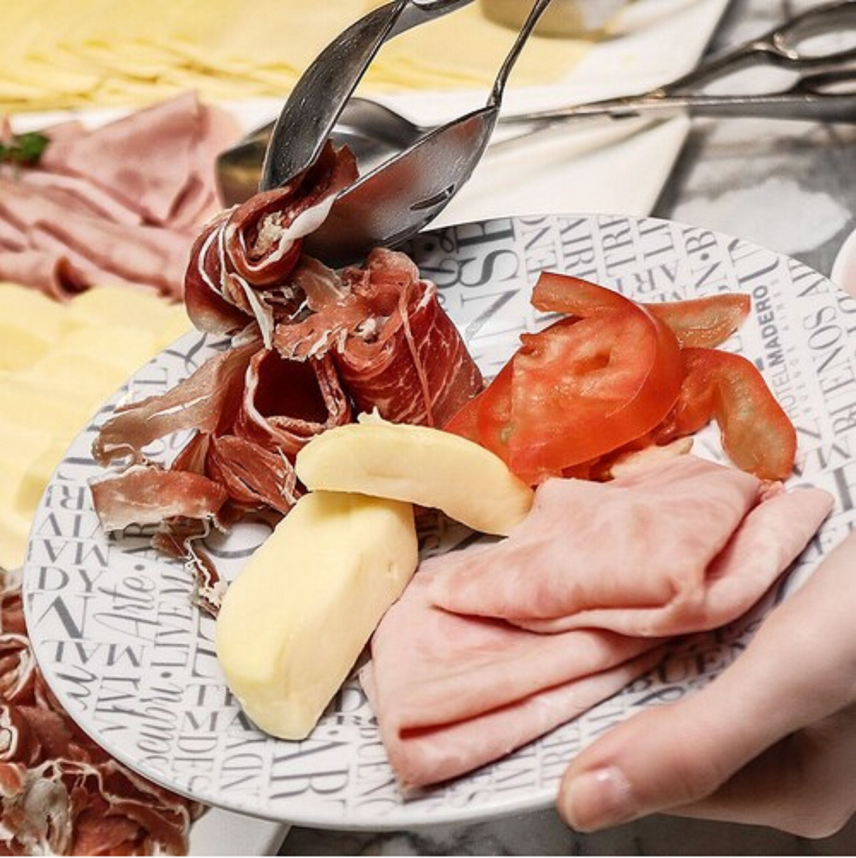 Um prato com diversos alimentos, incluindo presunto, tomates e queijo.