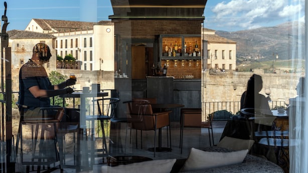 Um restaurante com mesas ao ar livre, um bar e vista para a paisagem urbana.