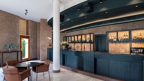 Uma área de bar com parede de tijolos, um balcão com garrafas e um espaço de estar com cadeiras.