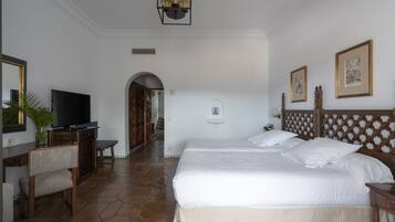 Quarto de hotel com uma cama grande, televisão, escrivaninha e uma cadeira.