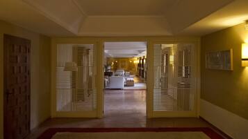 Um corredor com carpete vermelho que leva a um quarto com sofá branco e luminária.