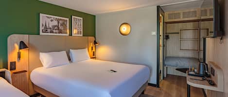 Quarto de hotel com uma cama grande, duas luminárias de cabeceira, uma luz na parede e uma pequena mesa com um controle remoto.