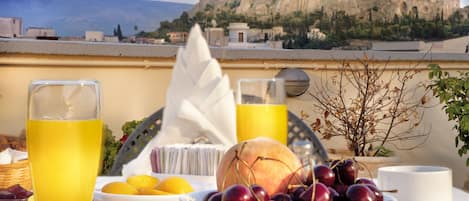 Mesa de café da manhã com frutas, suco e vista para ruínas antigas.