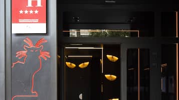 Entrada de hotel com placa vermelha exibindo a silhueta de um gato e classificação de cinco estrelas.