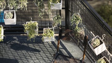 Um jardim no terraço com vários vasos de plantas e um corrimão de metal.