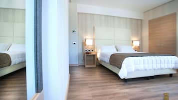 Quarto de hotel com duas camas, soalho em madeira e um guarda-roupa espaçoso.