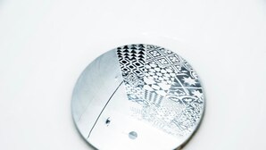 Um objeto redondo e refletor com padrões geométricos complexos.