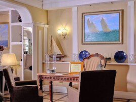 Uma área de refeições com uma mesa posta para o café da manhã, um quadro emoldurado de veleiros e um castiçal decorativo na parede.
