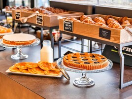 Vitrine de padaria com diversos produtos de panificação, como croissants e uma torta em um balcão.