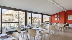 Uma sala de jantar moderna com janelas amplas, mesas e cadeiras brancas.