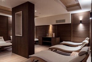 Um espaço de spa com duas poltronas reclináveis, um armário de madeira e um quadro na parede.