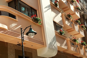Fachada de edifício com várias varandas, cada uma decorada com floreiras.