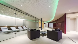 Um hall moderno com teto curvo, paredes de vidro e uma área de estar com sofás e mesa de centro.