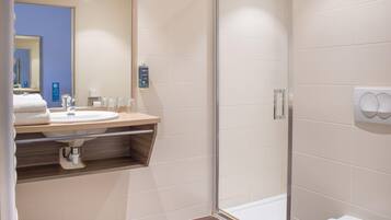 Casa de banho moderna com cabine de chuveiro em vidro, pia com espelho e porta-toalhas.