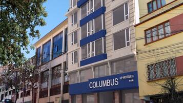 Um hotel chamado 'Columbus' com fachada moderna, vários andares e uma placa bem visível.