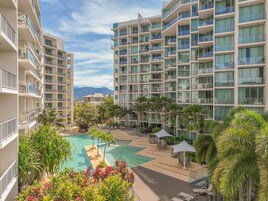 Um hotel com vários andares, varandas, piscina e jardins exuberantes.