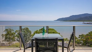 Varanda com mesa e cadeiras com vista para um corpo d'água e uma montanha ao longe.