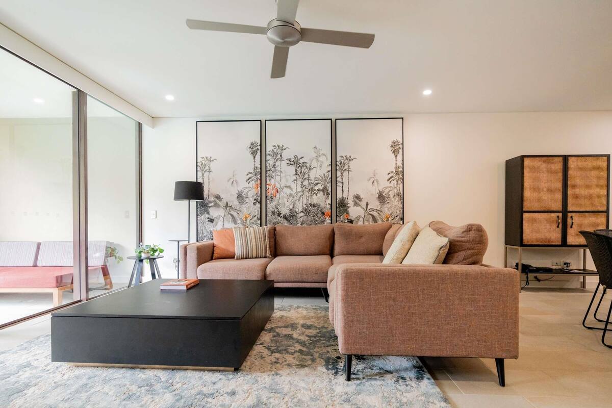 Uma sala de estar moderna com sofá seccional, mesa de centro e uma janela ampla.