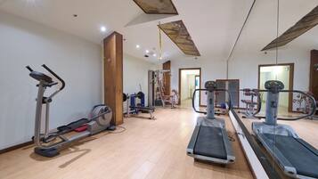 Uma academia com aparelhos de cardio, equipamentos de musculação e um espelho grande.