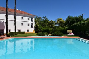 Uma piscina com um edifício branco ao fundo.