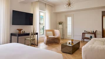 Quarto de hotel moderno com uma cama grande, uma escrivaninha, uma cadeira, uma mesa de centro e televisão fixada na parede.