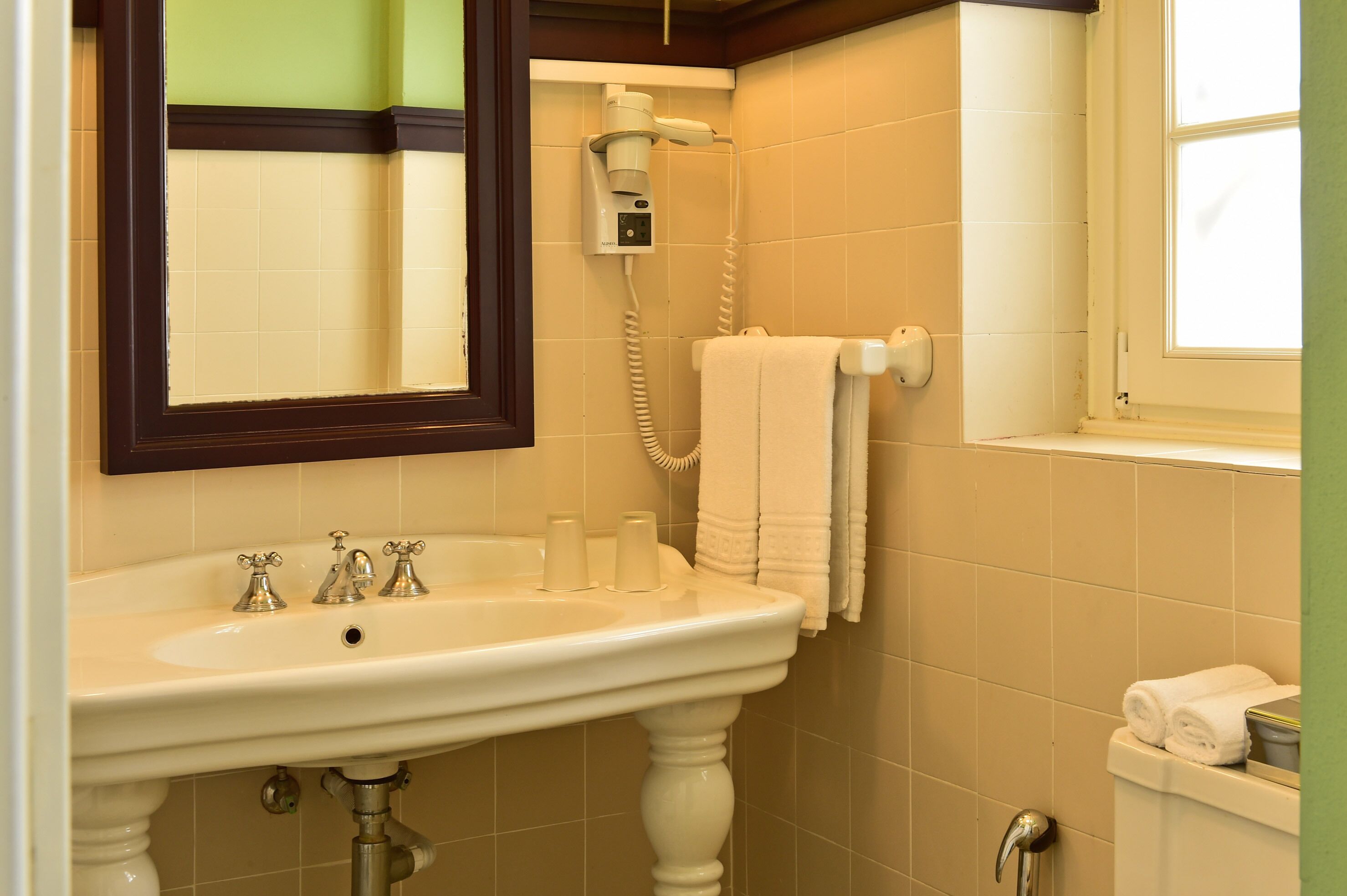 Casa de banho com lavatório, espelho, porta-toalhas e secador de cabelo.